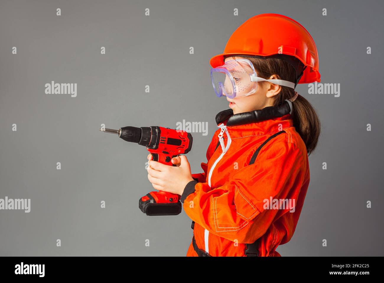 The little girl dressed in a red engineering uniform is holding a ...