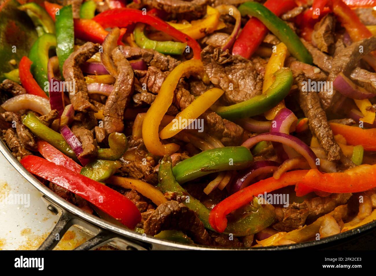 Cooking Mexican steak fajitas in giant pan on stovetop Stock Photo - Alamy
