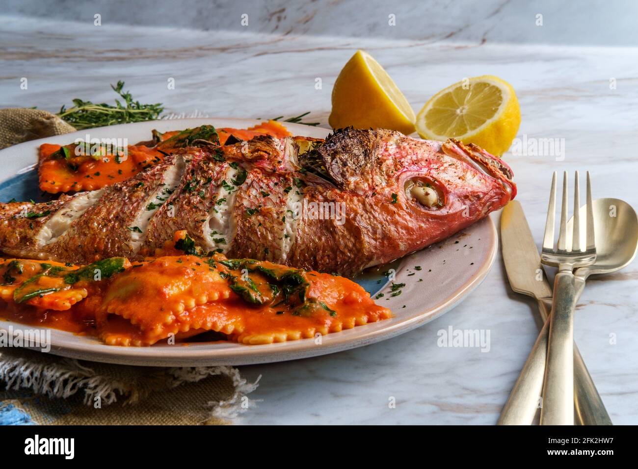 Whole head-on red snapper seafood dinner with ravioli in sherry wine pink sauce Stock Photo - Alamy