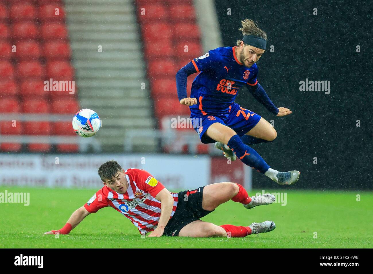 Luke Garbutt #29 of Blackpool leaps in the air to avoid being caught by ...