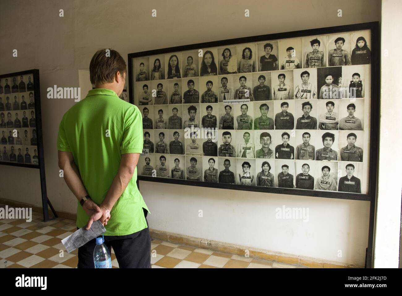 A tourist views photos of torture victims at Tuol Sleng Genocide Museum ...