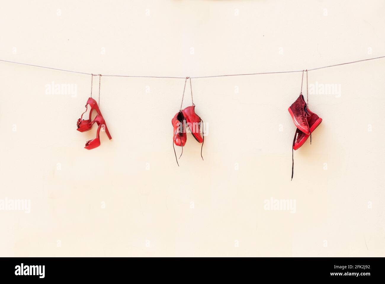 Three red shoes hanging by a thread Stock Photo - Alamy