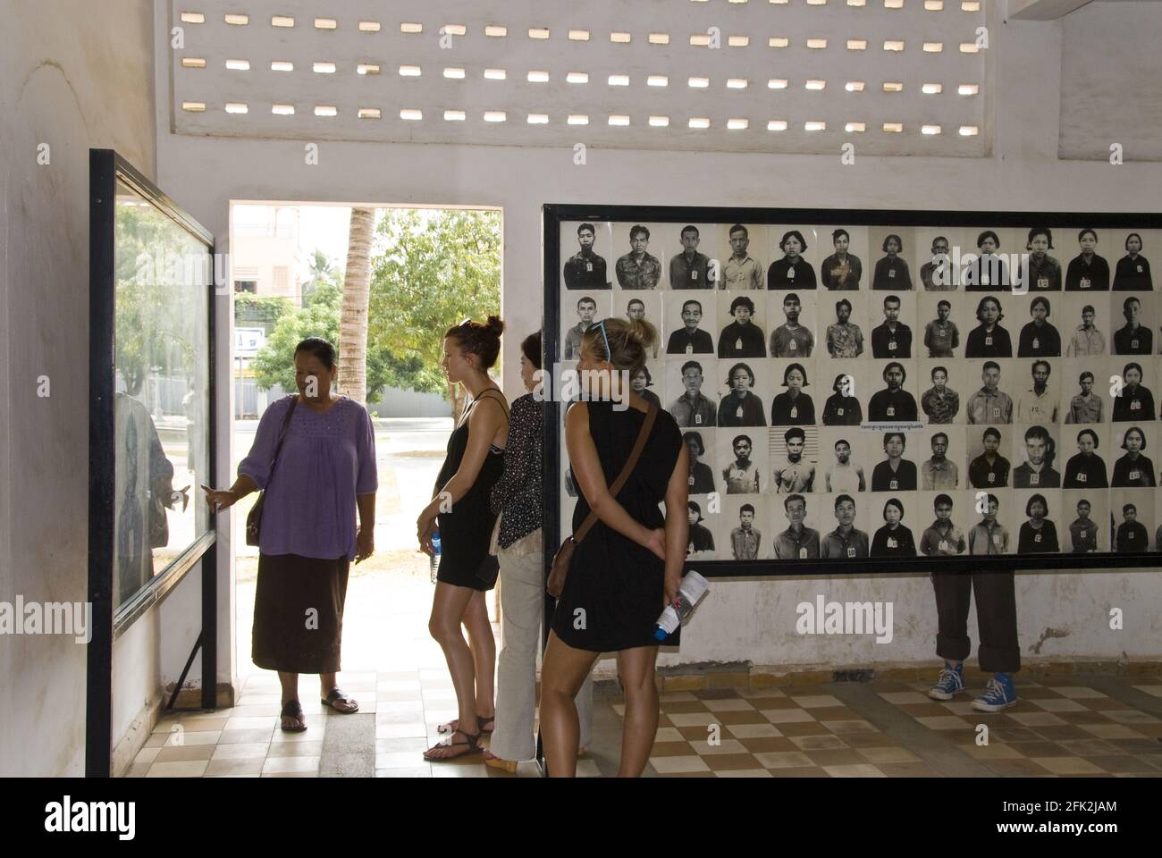 A guide and tourists view photos of prisoners at the Tuol Sleng ...
