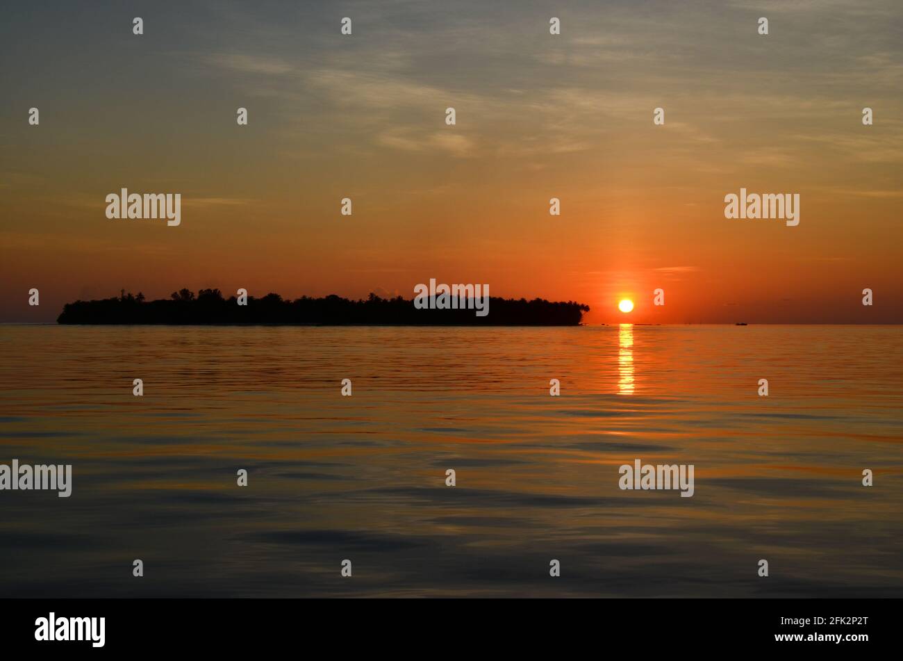 Orange-red sunset with a reflection of sunlight in the water next to a ...