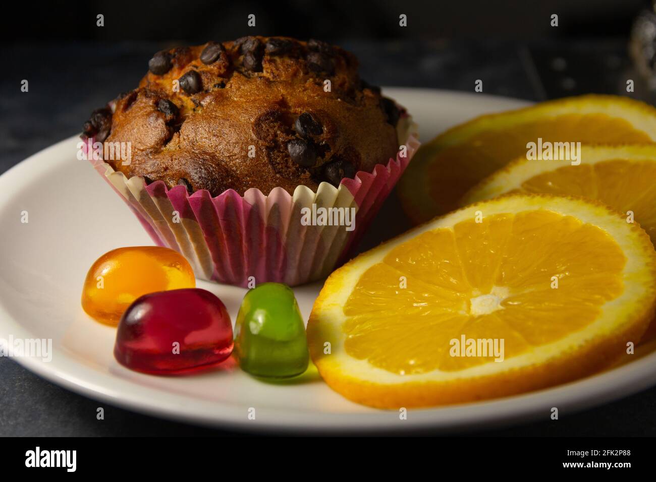 Tasty looking colorful dessert with oranges, muffins and sweets. Side ...