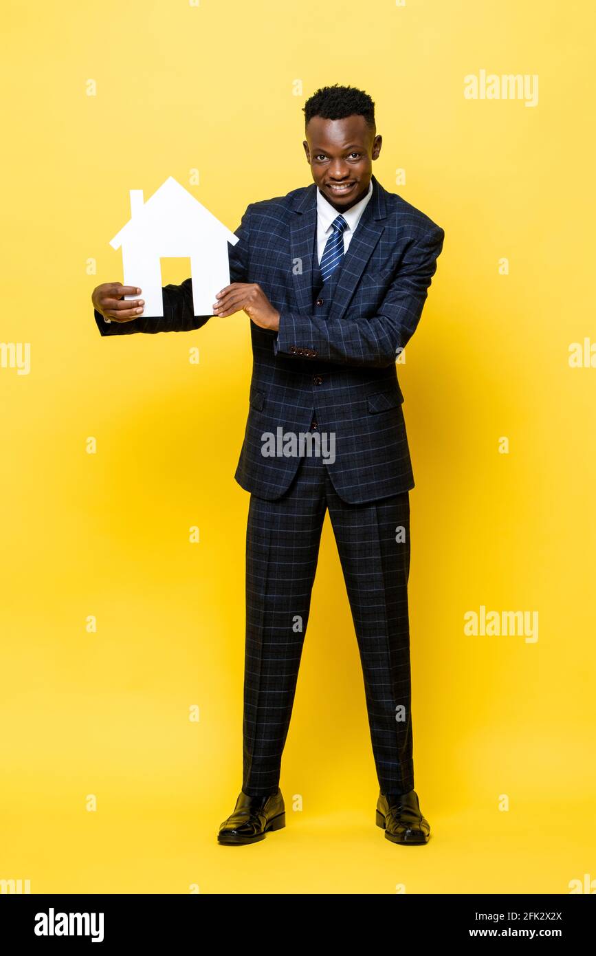 Young African businessman as a real estate agent holding house cutout ...