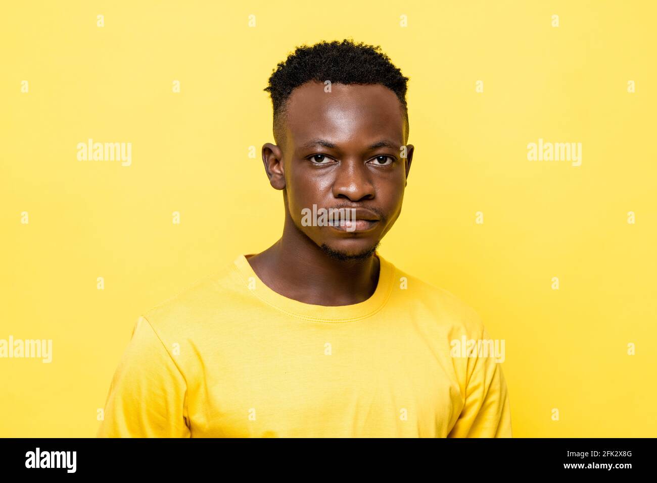 Close up portrait of young African man face on isolated yellow studio ...