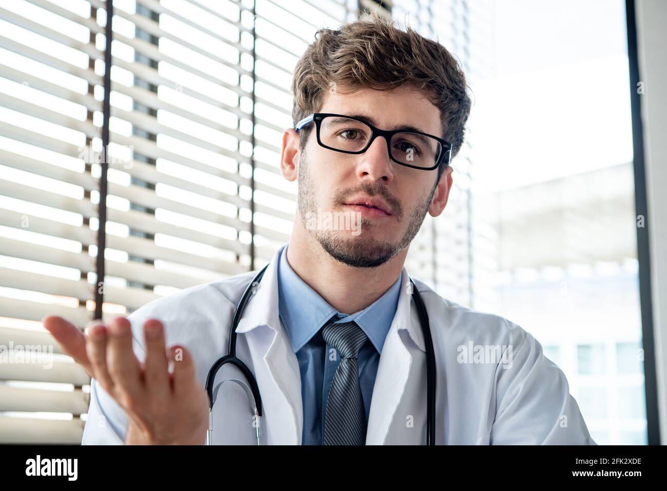 Close up shot of young male doctor looking at camera explaining to ...