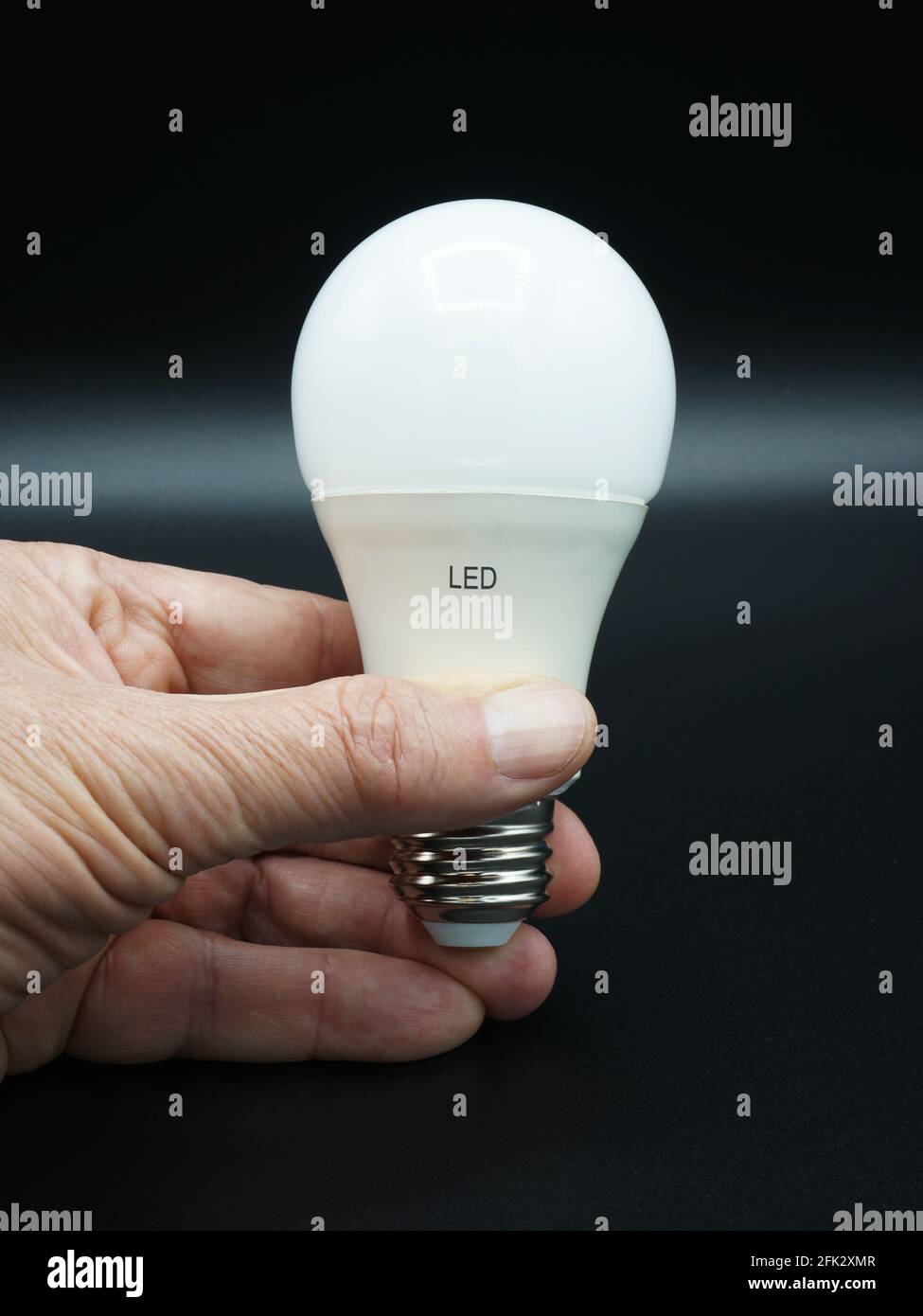 Man's hand holding LED light bulb. Close-up. Isolated on black Stock ...