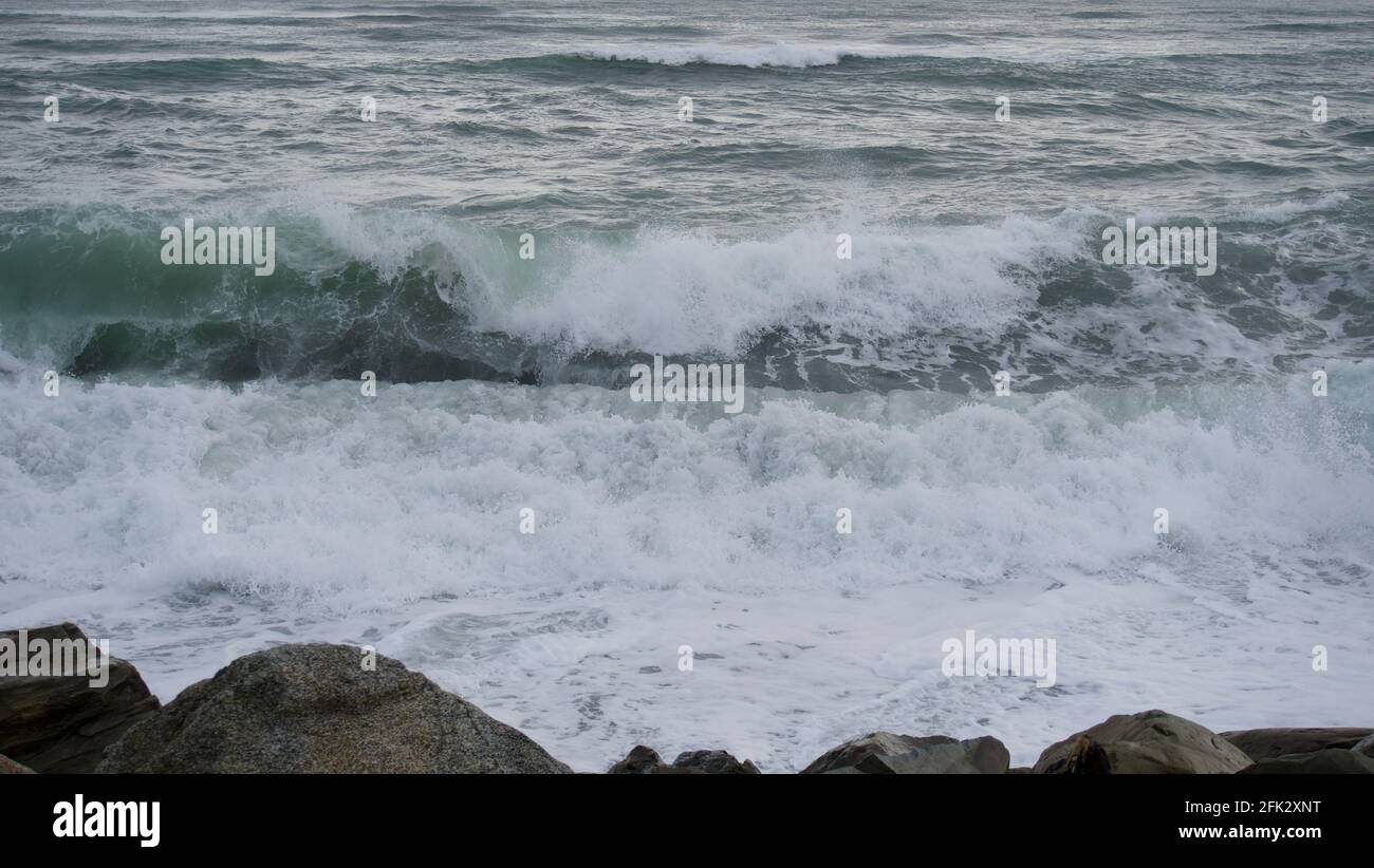 Angry wave coming towards rocks on the shore Stock Photo - Alamy