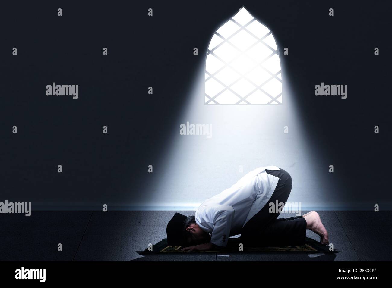 Asian Muslim man in praying position (salat) on prayer rug inside the ...