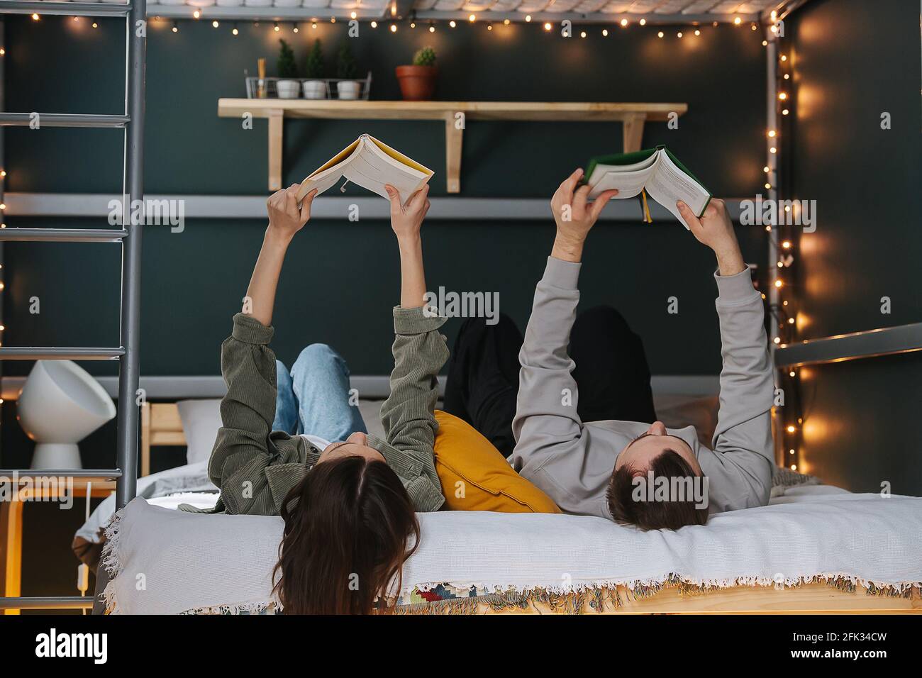 Funny couple reading books in bed, holding them in outstreched arms ...