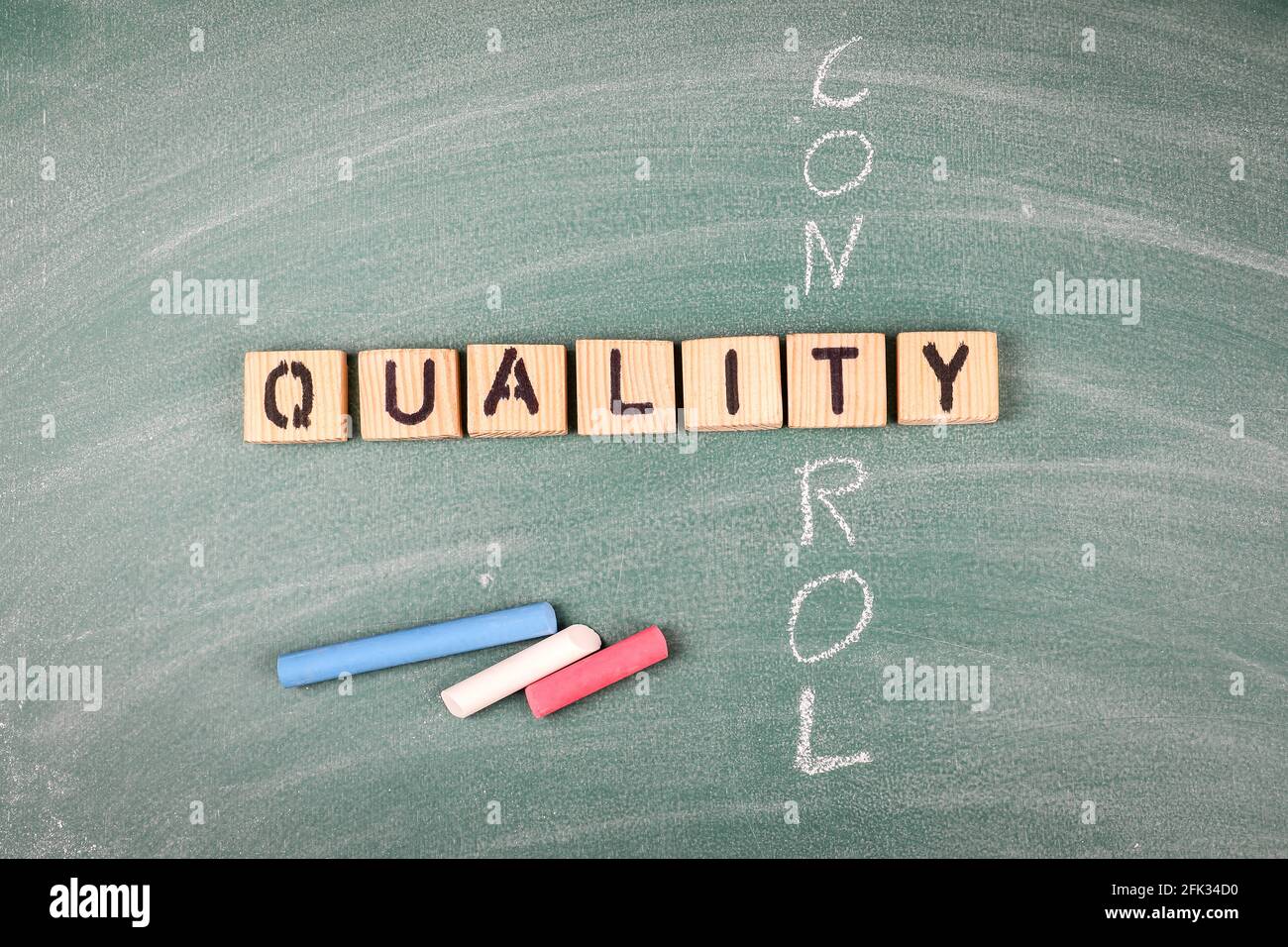 Quality and Control. Wooden alphabet letters on a green chalk board ...
