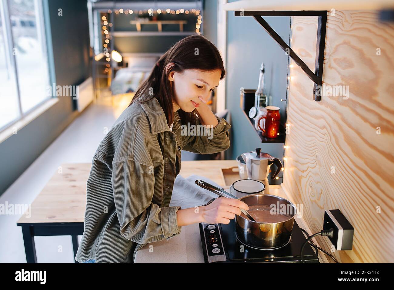 Patient woman cooking on a high kitchen table, she's stirring soup on a ...