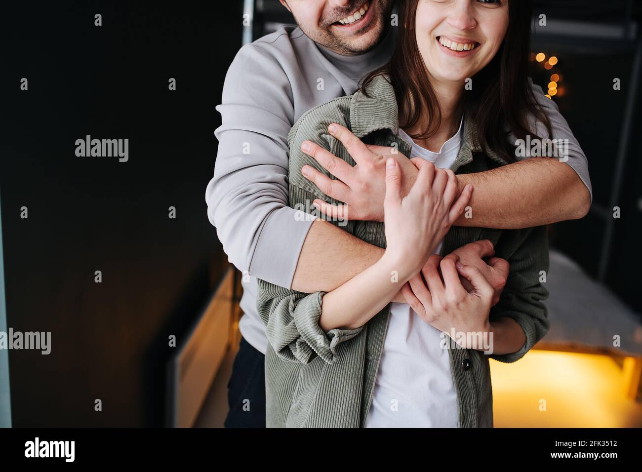 Cropped image of a happy loving couple. Man hugs woman from behind ...