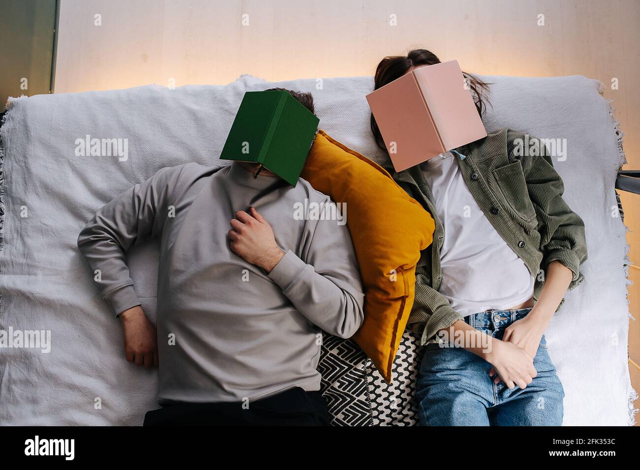 Cute funny couple napping with face covered with a book. Top view ...