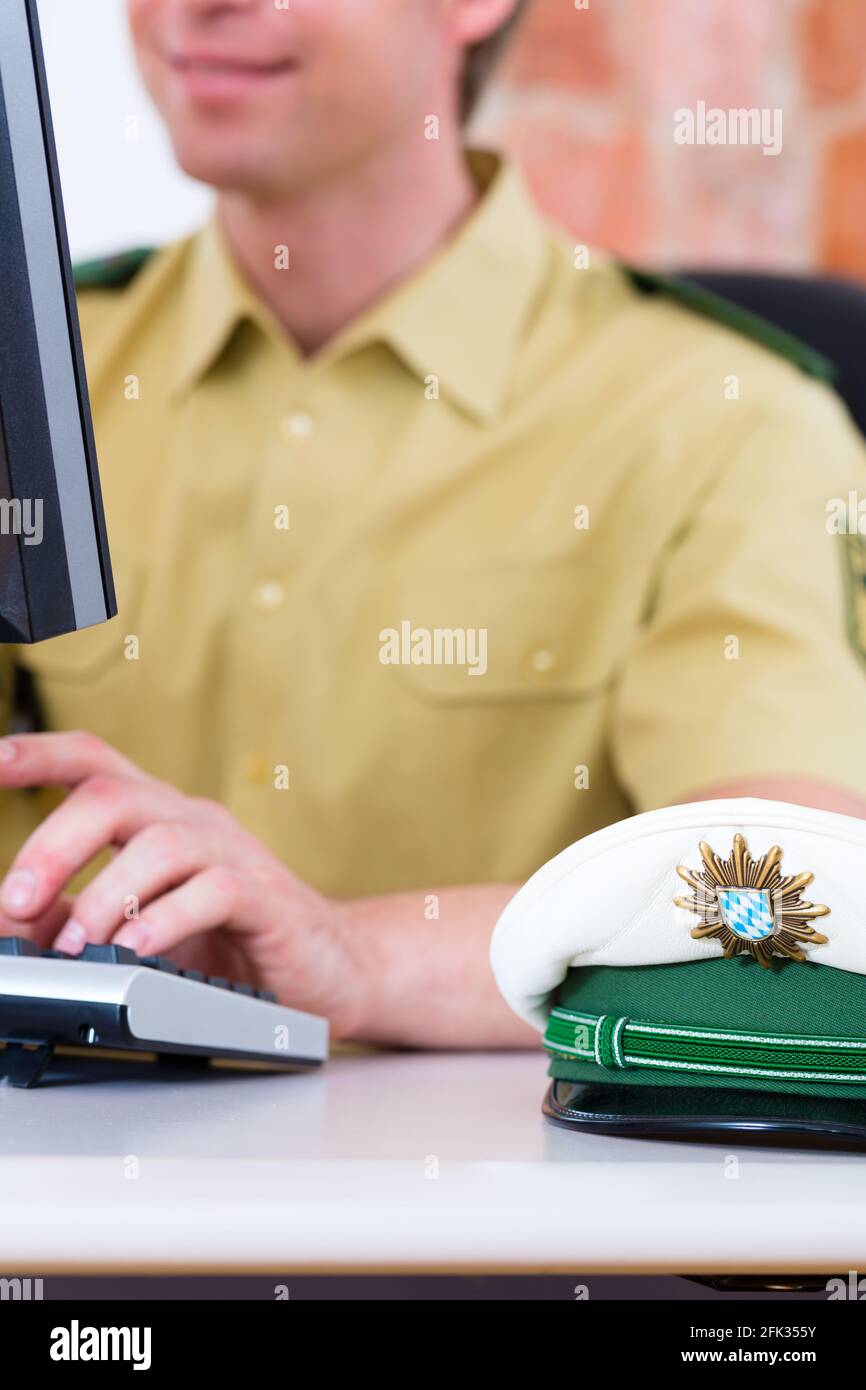 Police officer in police station working on the computer, on a case or ...