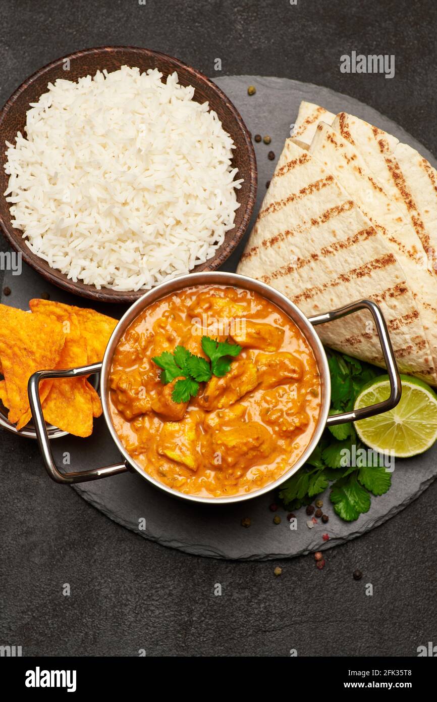Pot of Traditional Chicken Curry, bowl of rice and pita on stone ...