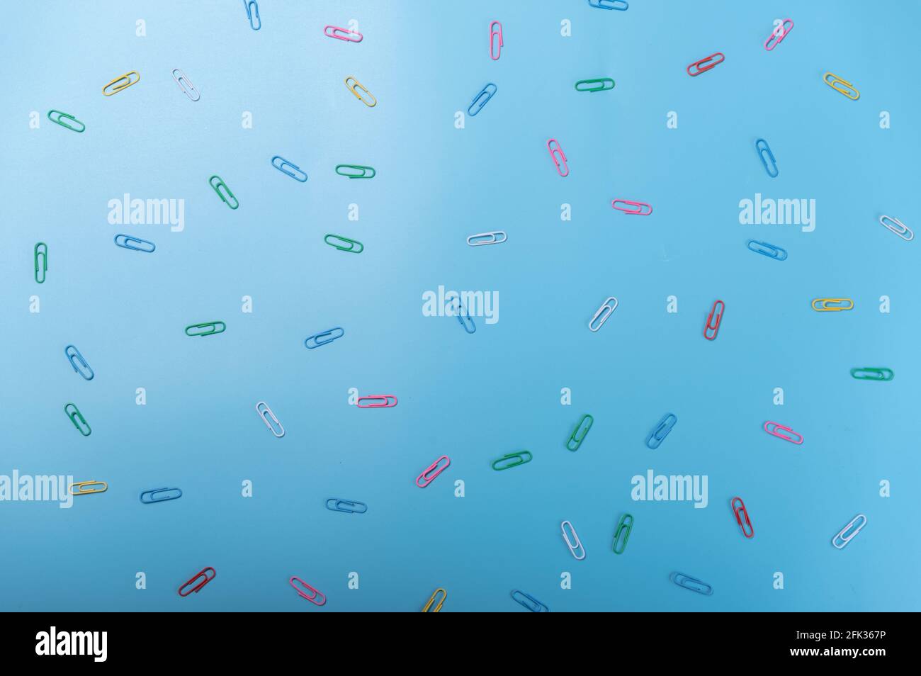 Multicolored paper clips on a blue background. Scattered paper clip on ...