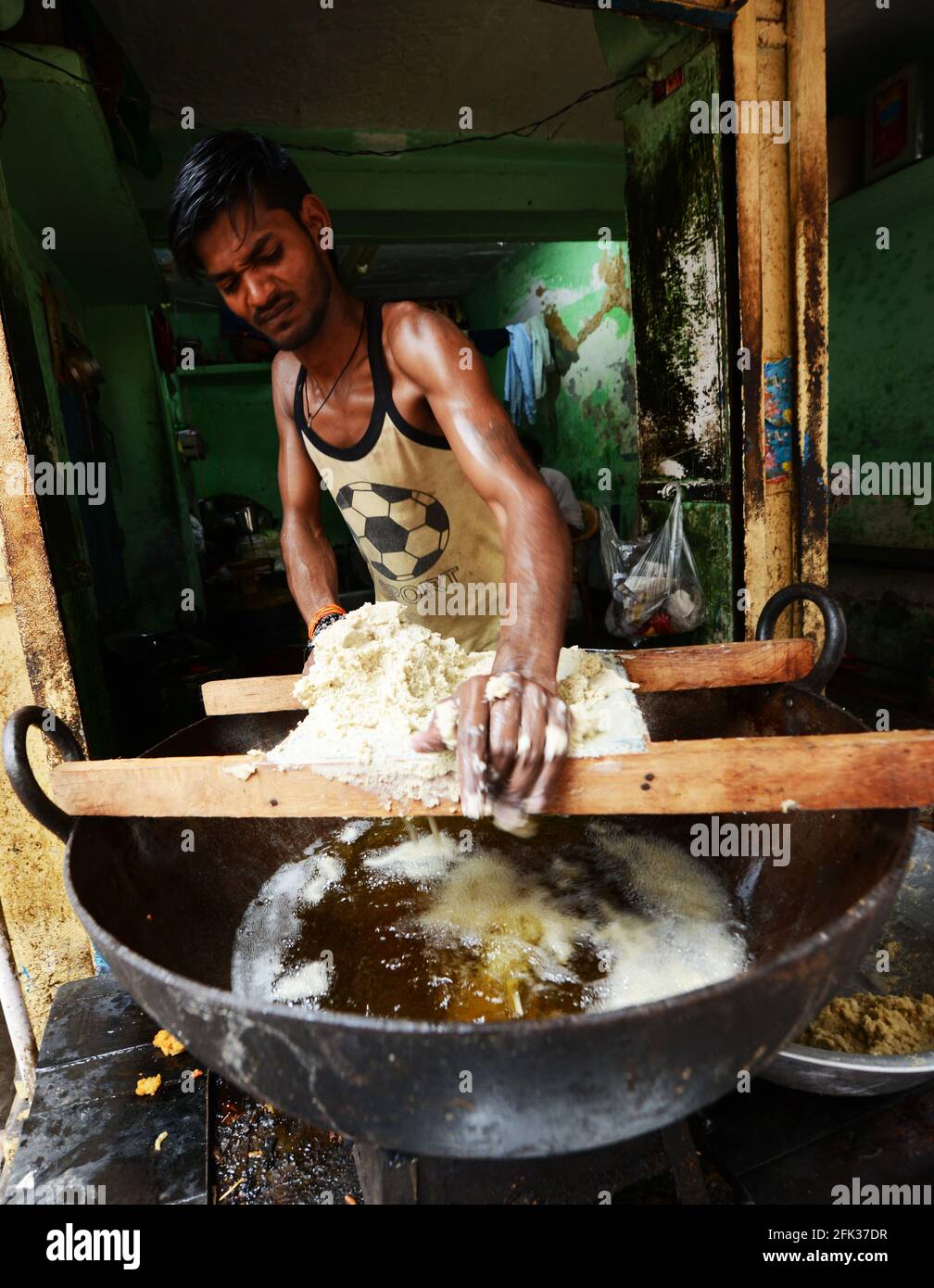 An Indian man preparing deep fried snacks in a small shop in the old ...