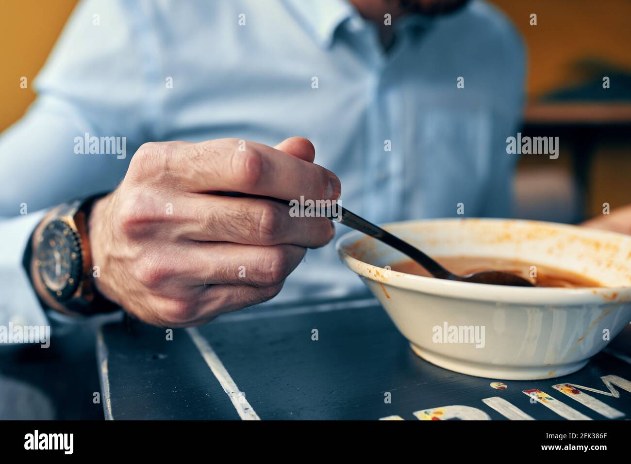 a man eats borscht with sour cream in a restaurant at a table in a cafe ...