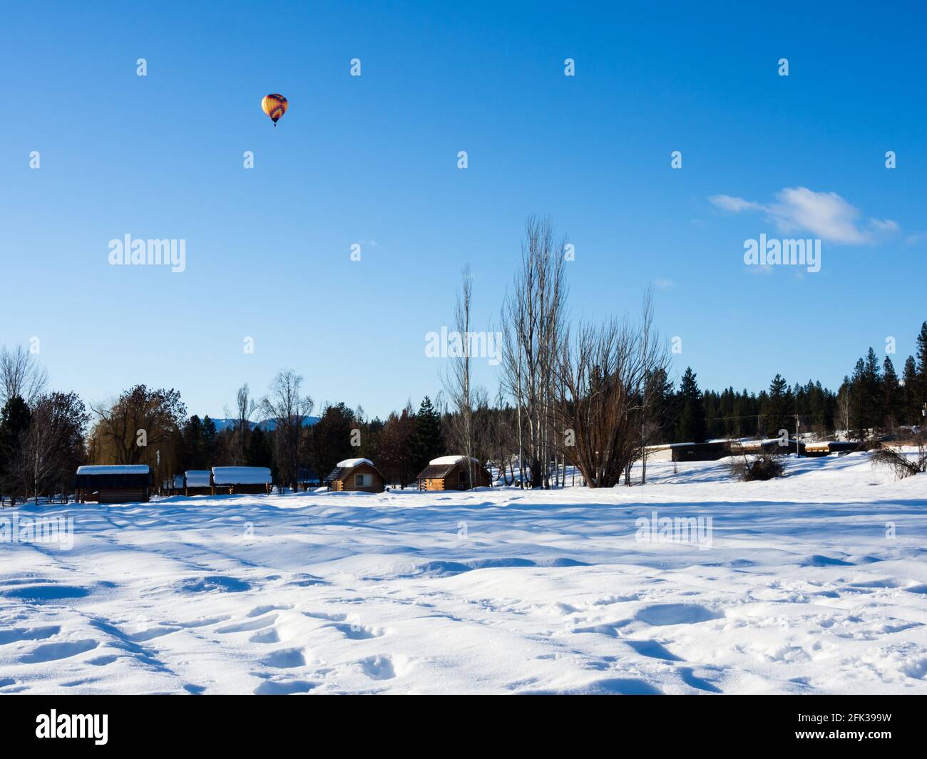 Colorful hot air balloon flying above a snow covered field at Winthrop ...