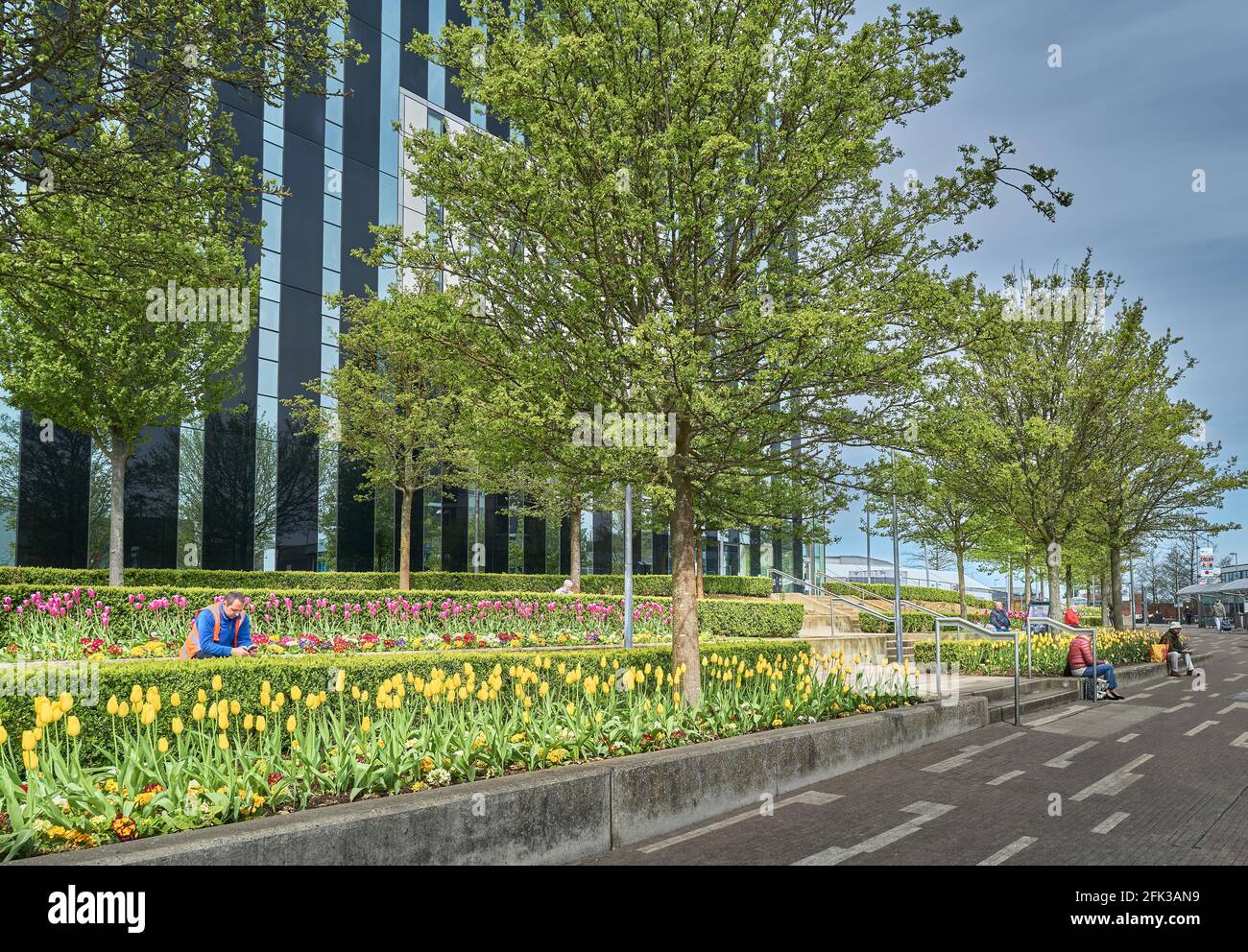 People sit and relax outside the Cube glass building in the town centre ...