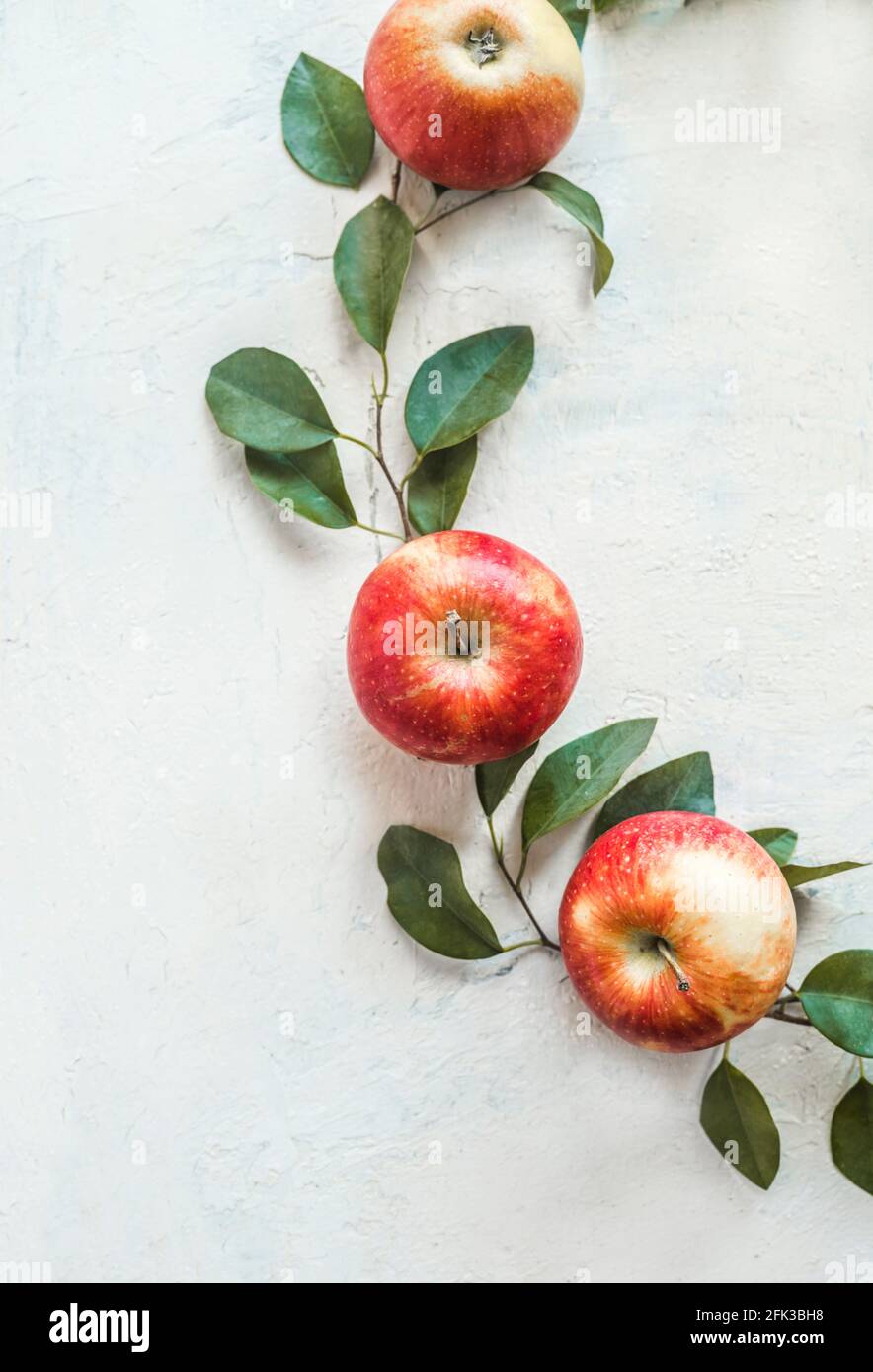 Fresh red apples with green leaves on white desk background. Top view ...