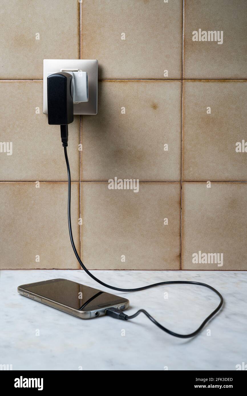 a mobile phone connected to a phug for charging Stock Photo - Alamy