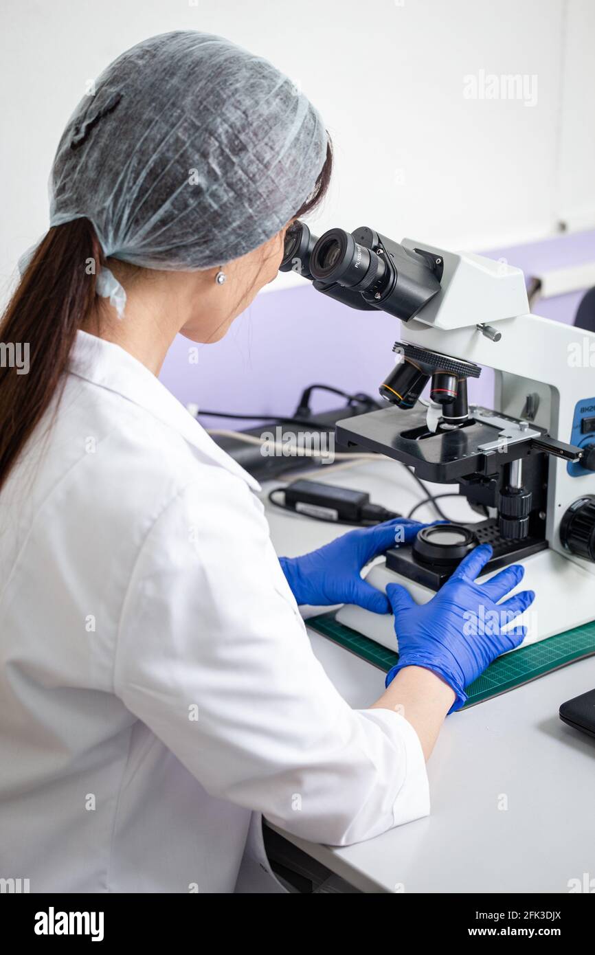 Girl lab technician works on a microscope in a white cabinet Stock ...