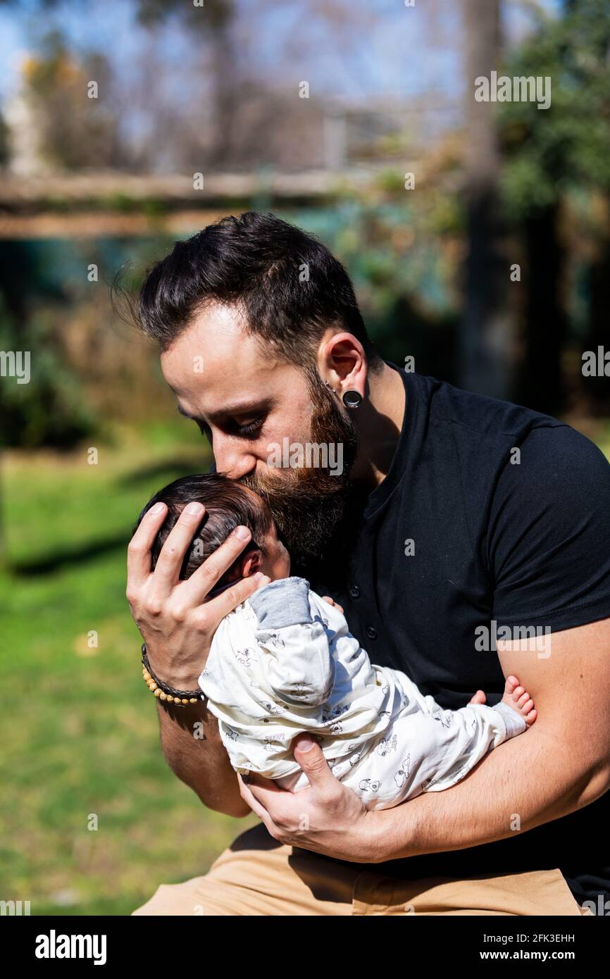 Happy young father hugging and kissing his sweet adorable newborn child ...
