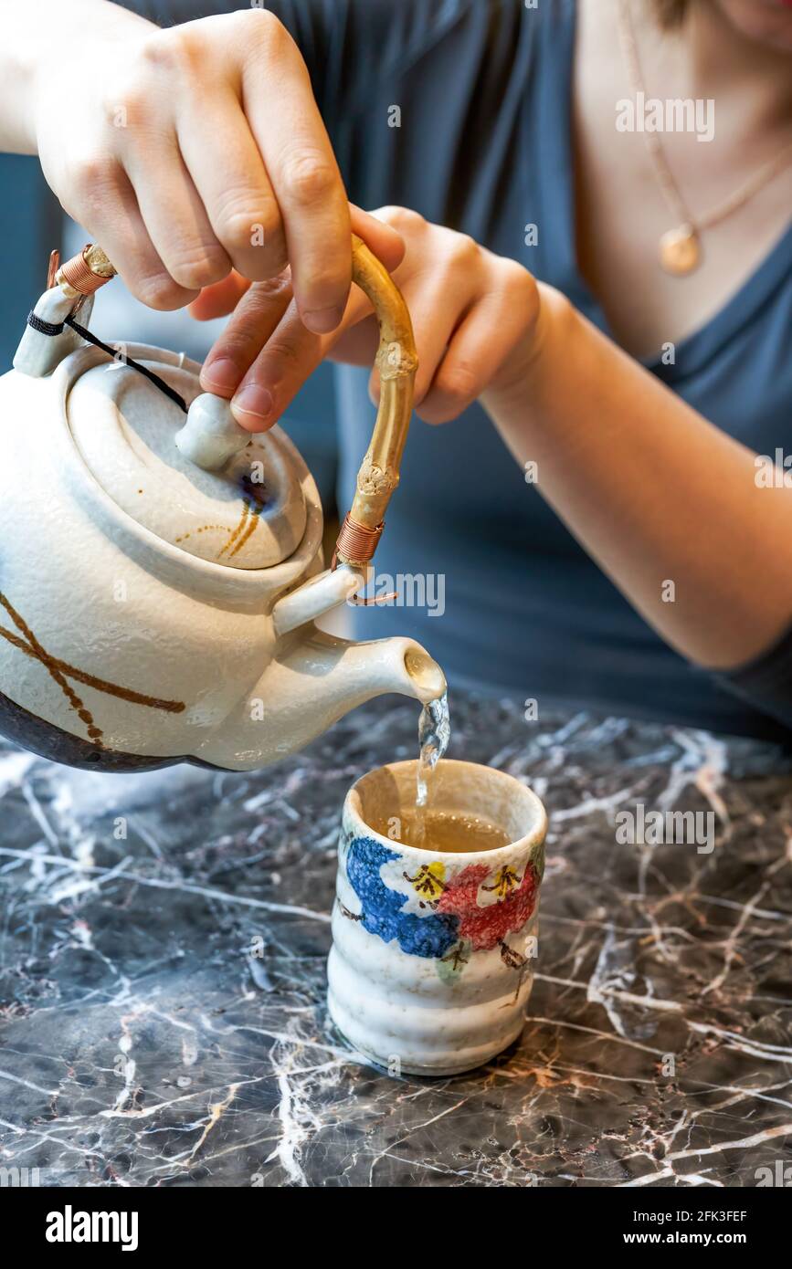 A woman is pouring tea with a Japanese style teapot Stock Photo - Alamy