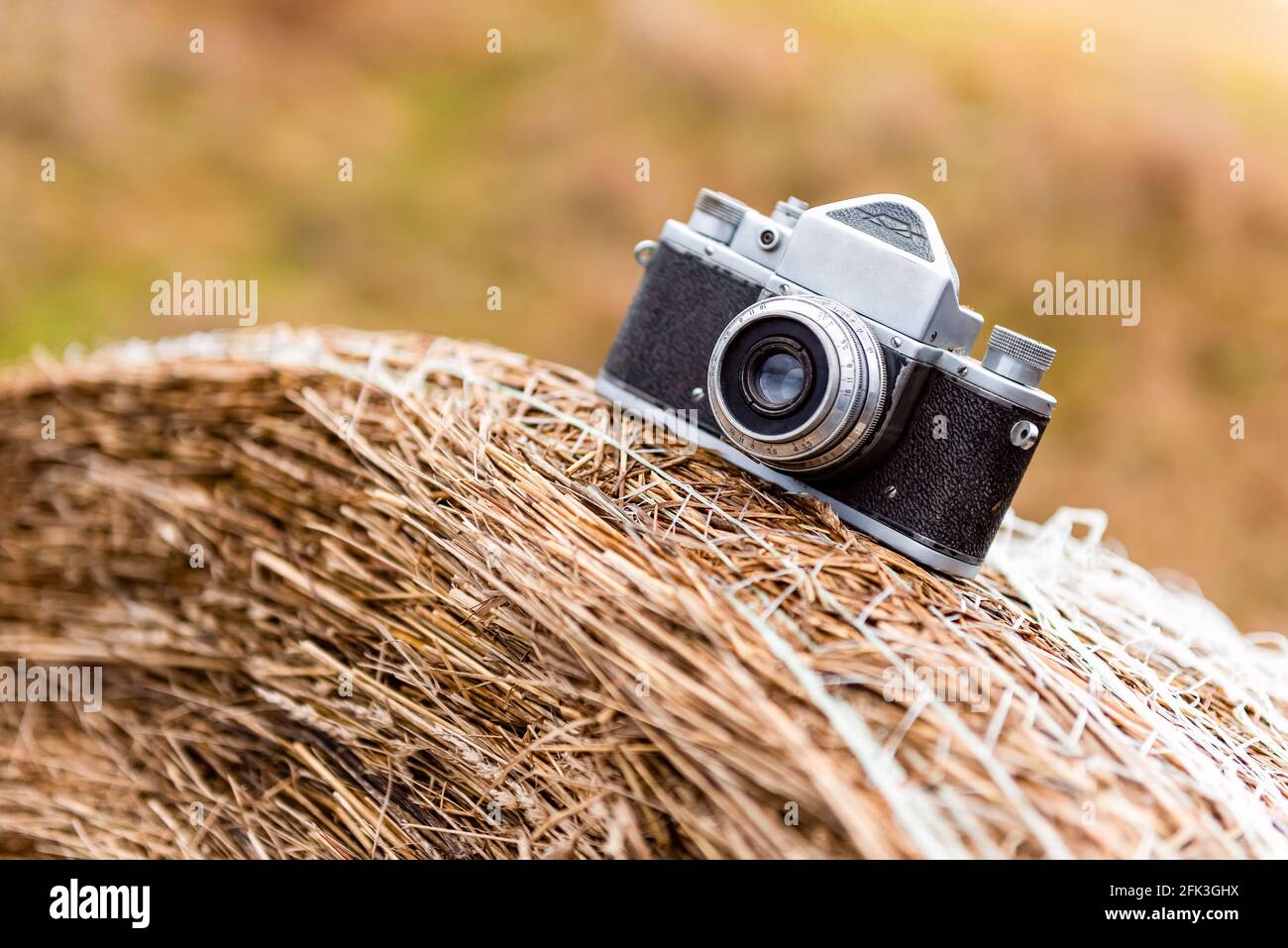 old film camera laying on a stack of hay, natural background ...