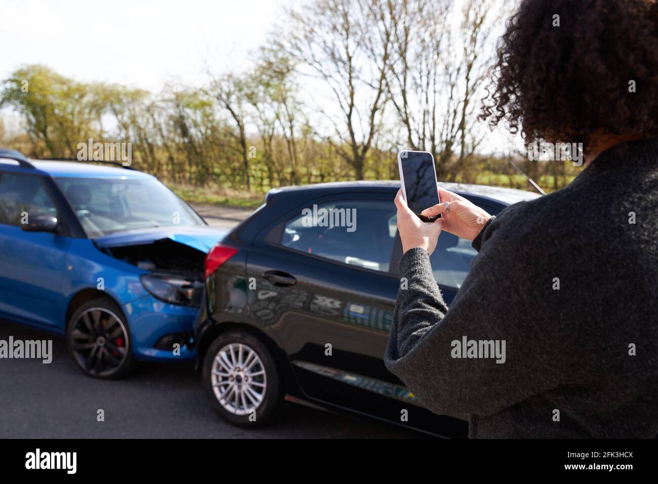 Rear view of female driver taking photos of road traffic accident on ...