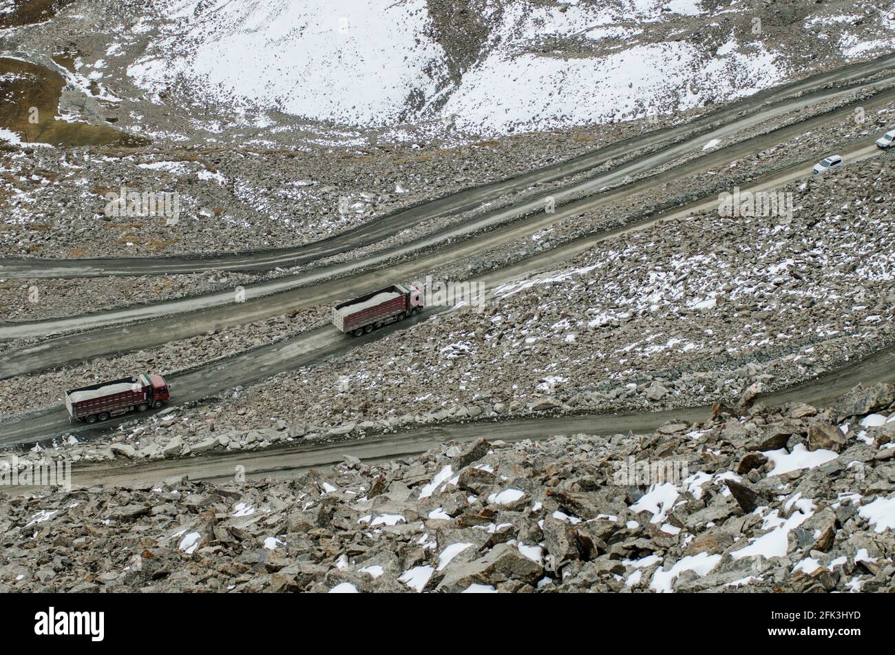 Heavy freight trucks and articulated lorries navigate along the unpaved ...