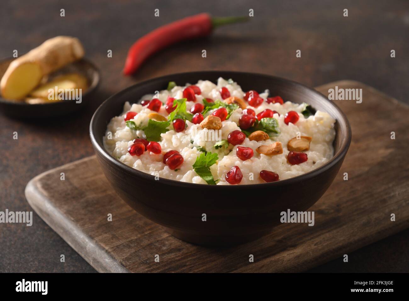 Curd Rice with pomegranate, cilantro, mustard seeds, ginger on a dark ...