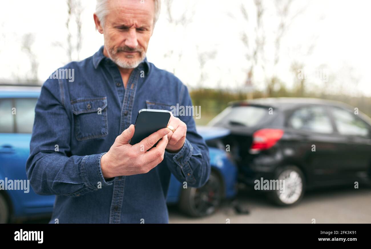 Senior man standing by damaged car after traffic accident calling ...