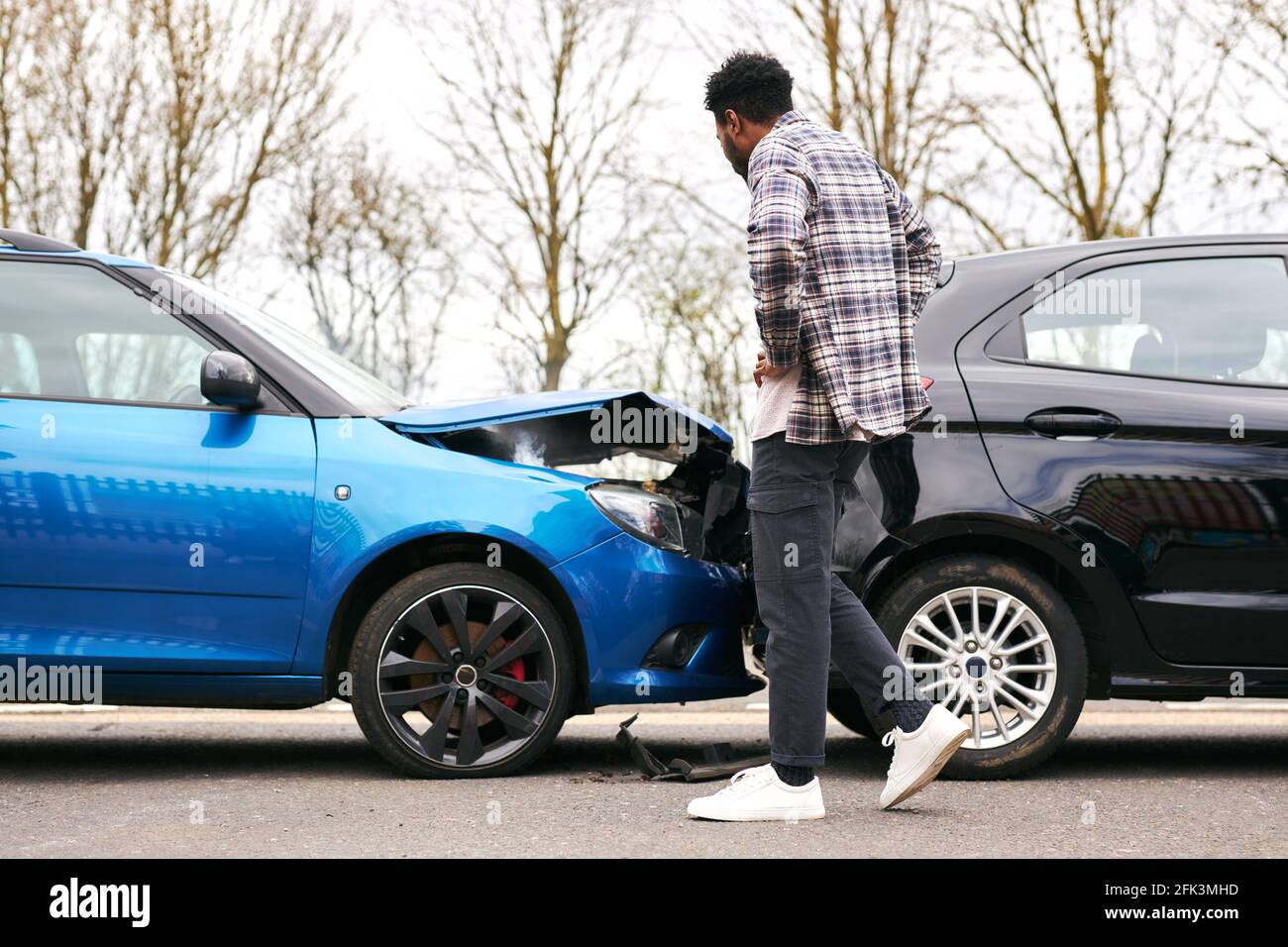 Young man looking at damaged car hit from behind after traffic accident ...