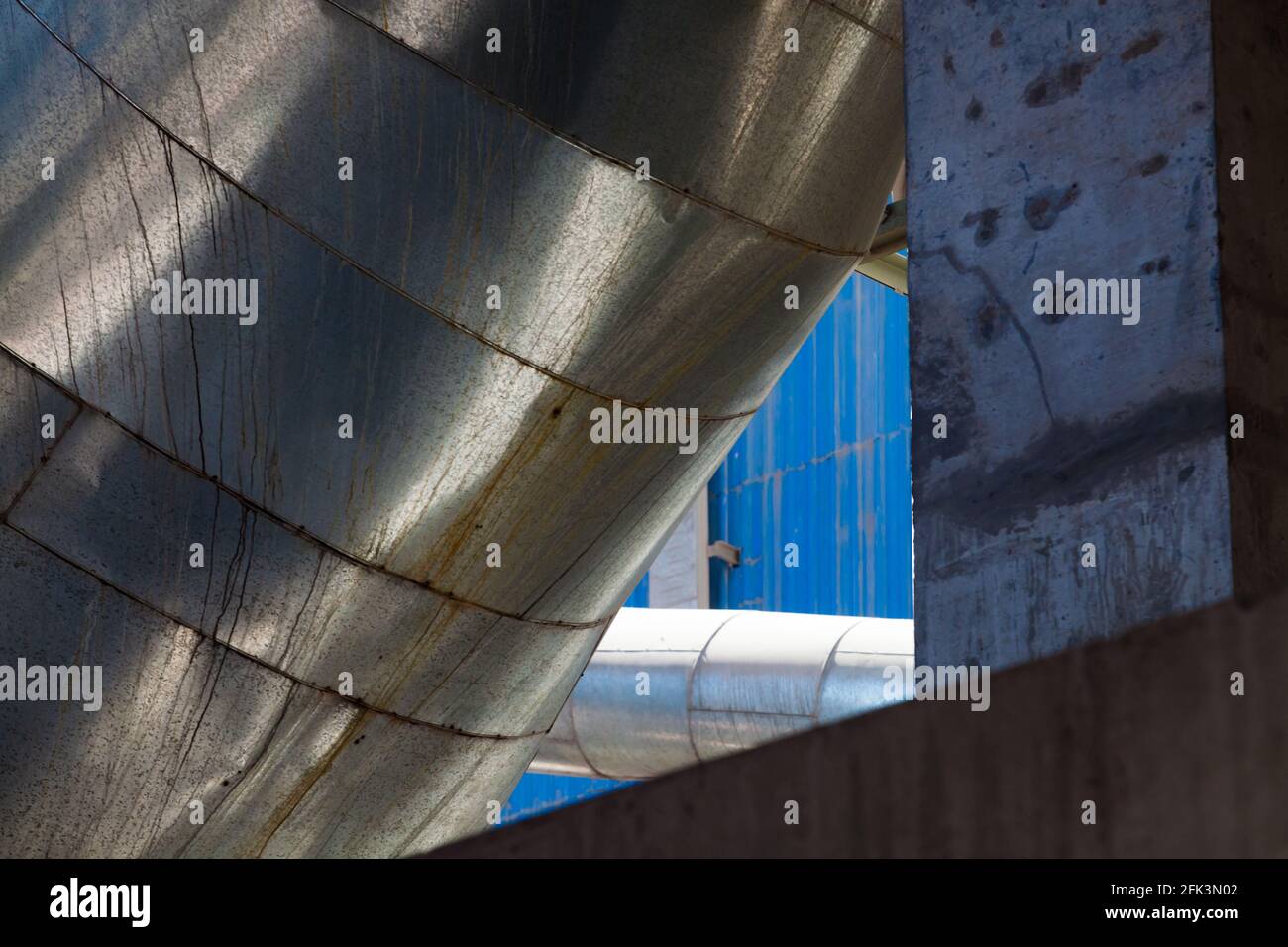 Cement plant. Galvanized metal tubes on blue wall backdrop. Abstract ...