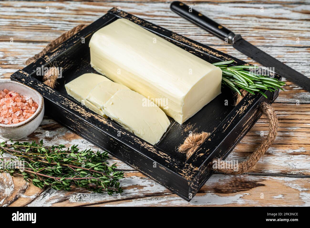 Butter Margarine block in a wooden tray with herbs. White wooden ...