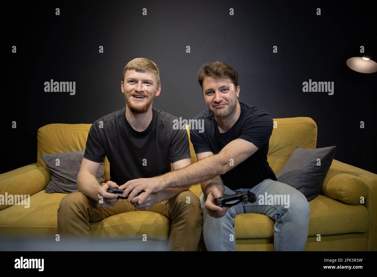 two cheerful handsome guys play passionately video game holding console ...