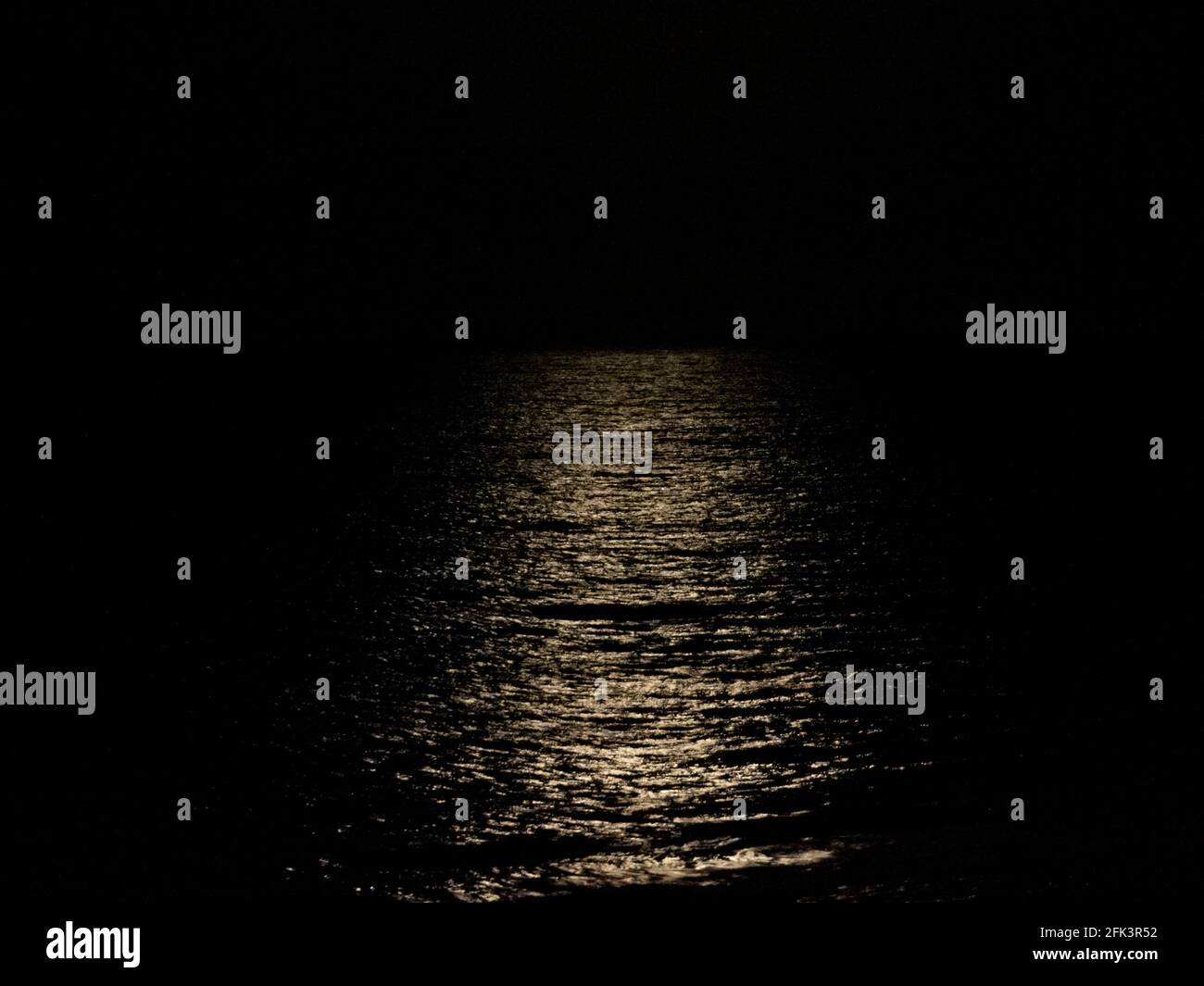 Reflections of moonlight on the surface of the sea on a dark night ...