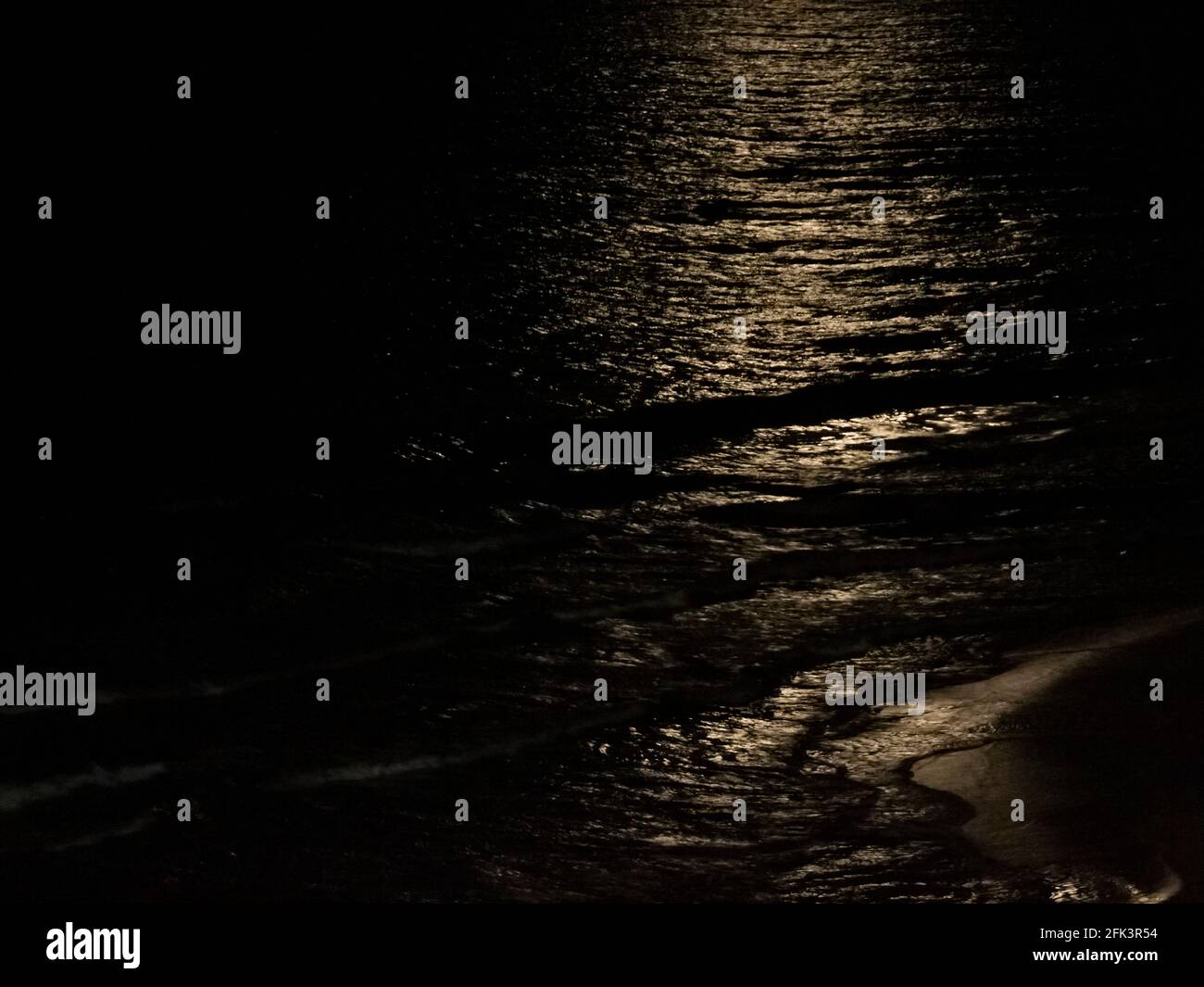 Reflections of moonlight on the surface of the sea on a dark night ...