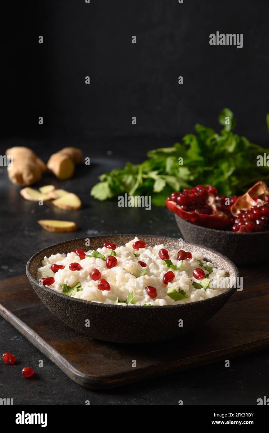Curd Rice with pomegranate, cilantro, mustard seeds, ginger on a black ...