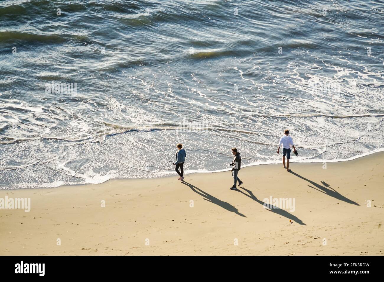 Three friends strolling on a beach seen from above Stock Photo - Alamy