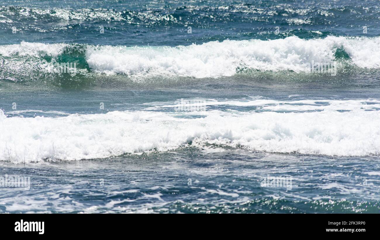 Surf coming at the camera in two surf lines on glittering water Stock ...