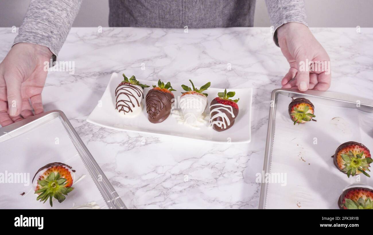 Step by step. Arranging chocolate strawberries on a white serving plate ...
