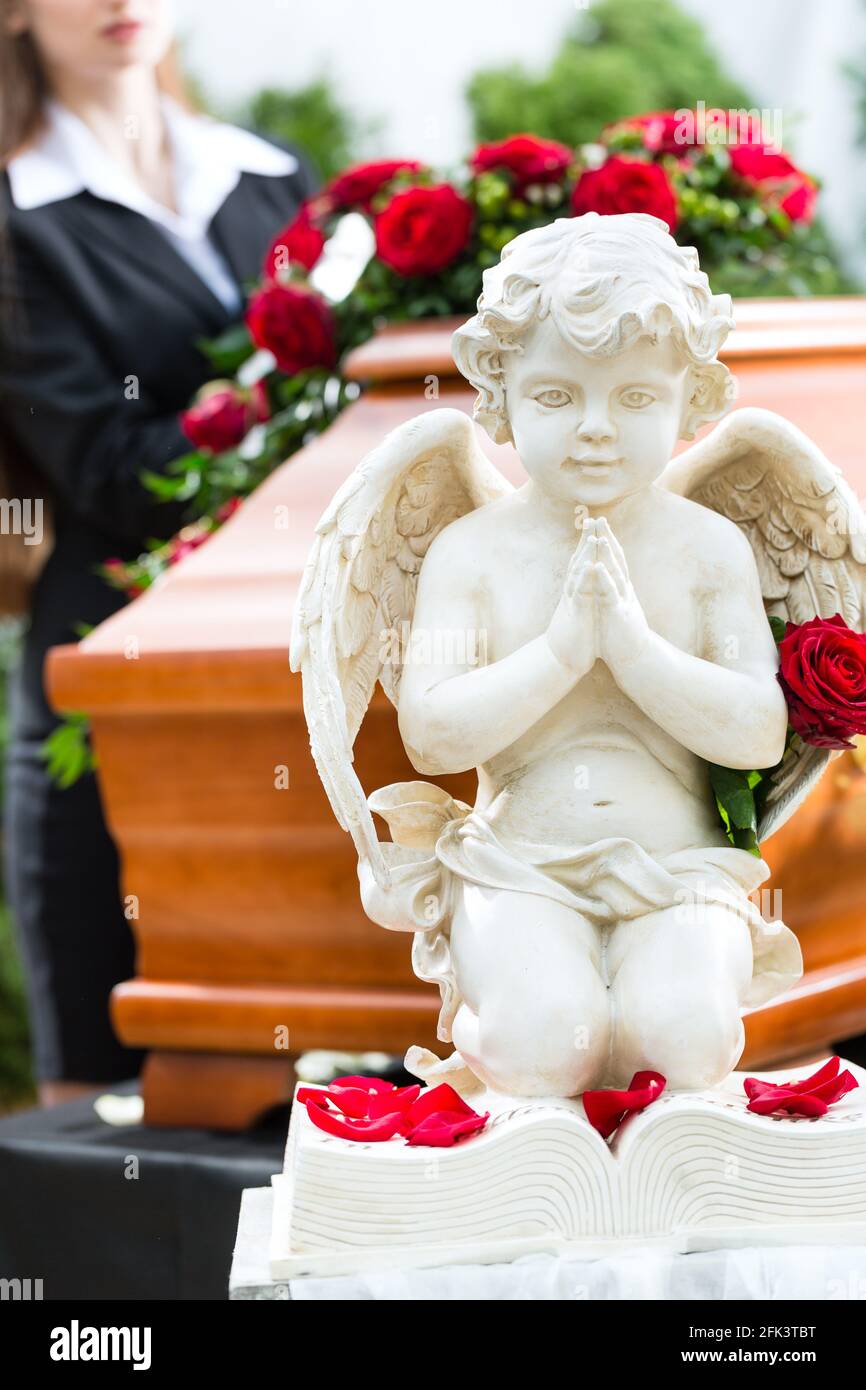 Mourning woman on funeral with red rose standing at casket or coffin ...