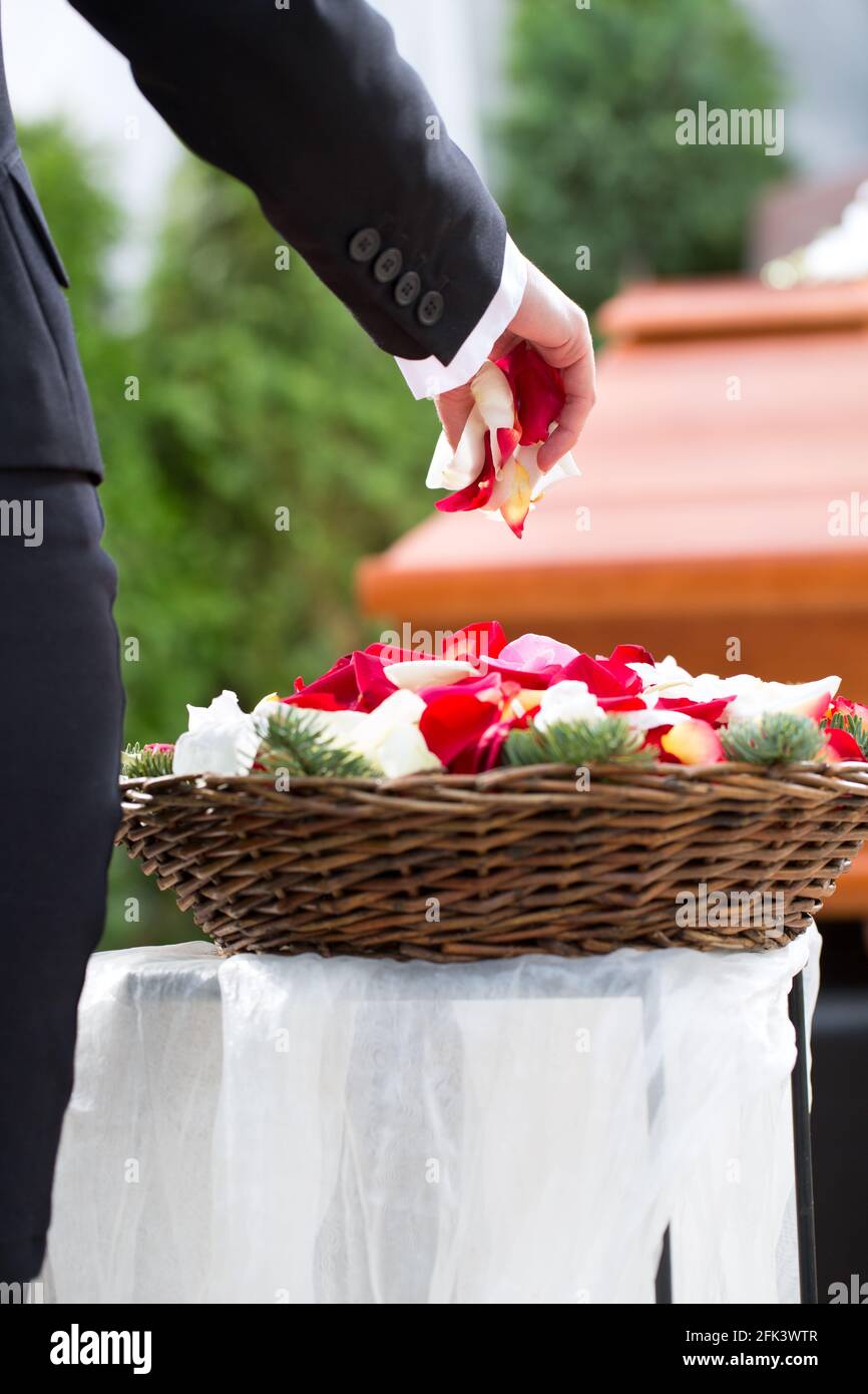 Mourning woman on funeral with flowers standing at casket or coffin ...