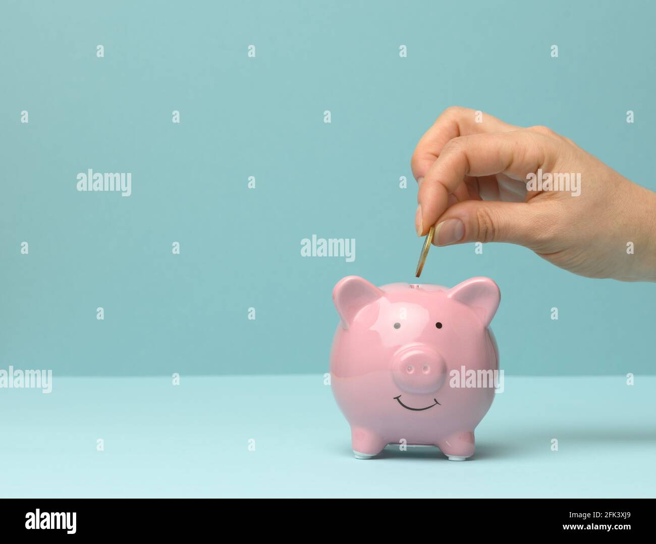 ceramic pink piggy bank and hand throwing a coin inside, finance ...